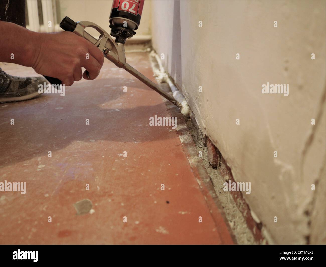 filling with mounting foam the gap between the wall and the floor in ...