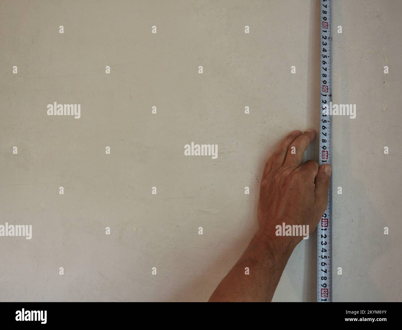 a male hand holds a metal tape measure ruler in centimeters attached to ...