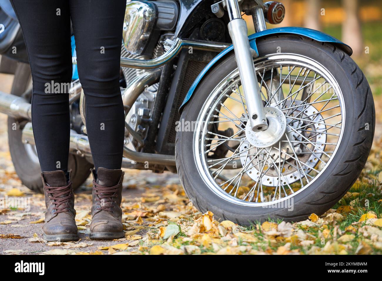 Female legs in leather motor boots standing near a classic motorcycle ...