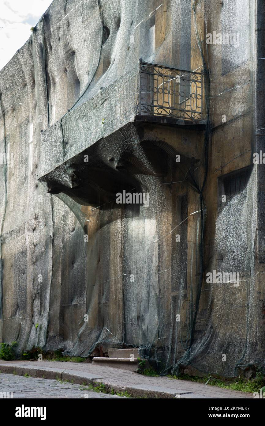 Old multi-storey building with balcony closed with construction grid ...