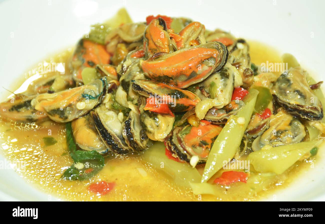 spicy stir fried mussel with slice onion and basil leaf on plate Stock ...