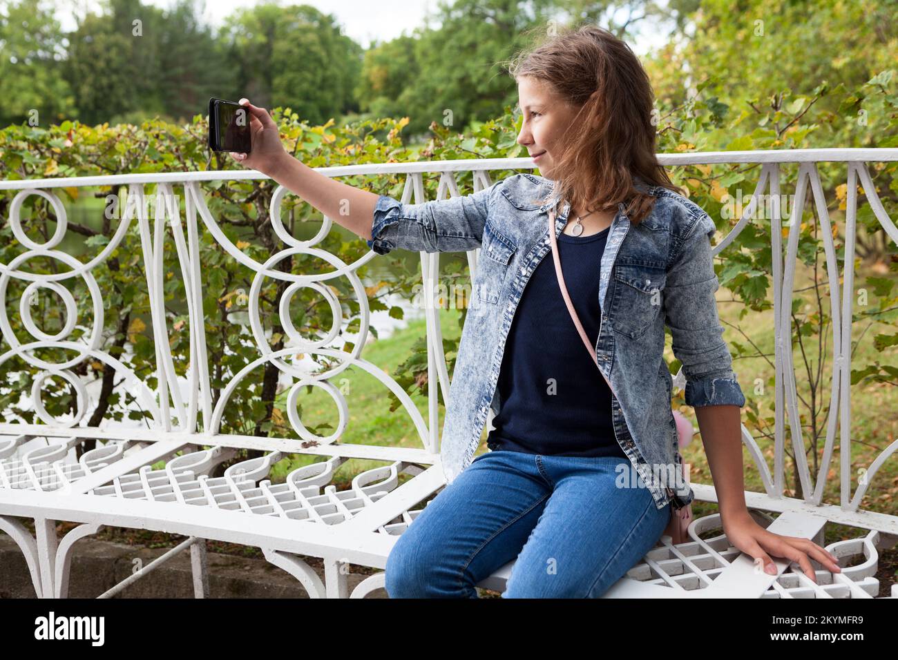 Teenage girl taking a selfie with her smartphone while sitting on a ...