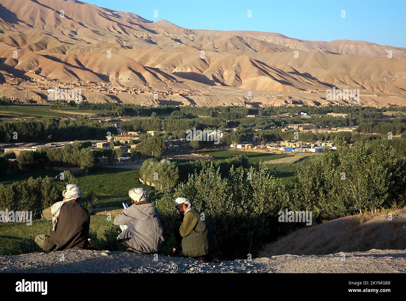 Bamyan (Bamiyan) / Central Afghanistan: Three Afghan men sit on a hill ...