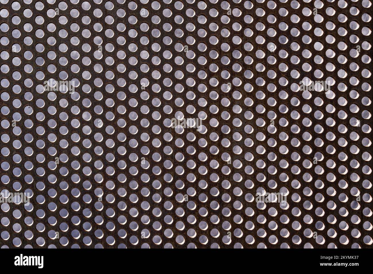 background of perforated rusty metal wall with dots, stucco wall behind ...