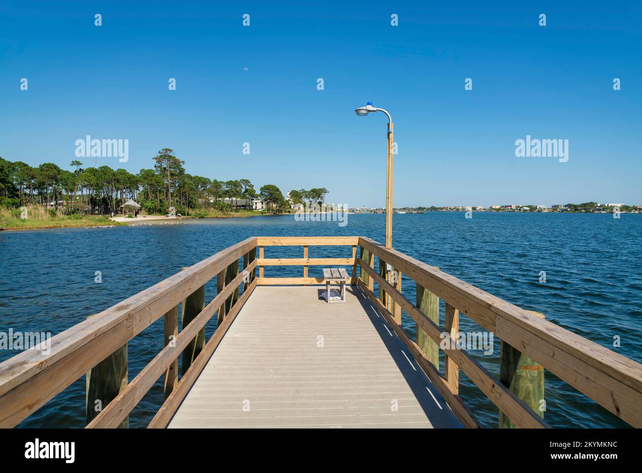 End of the pier with wooden chair below the light post and a view of a ...