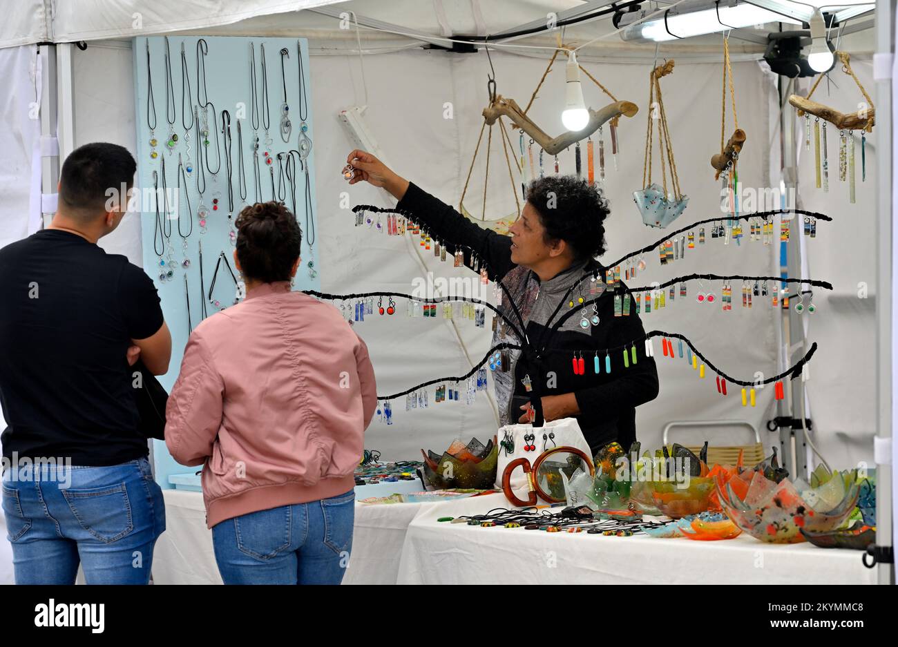 Jewellery stall at market with sales person pointing out item to ...