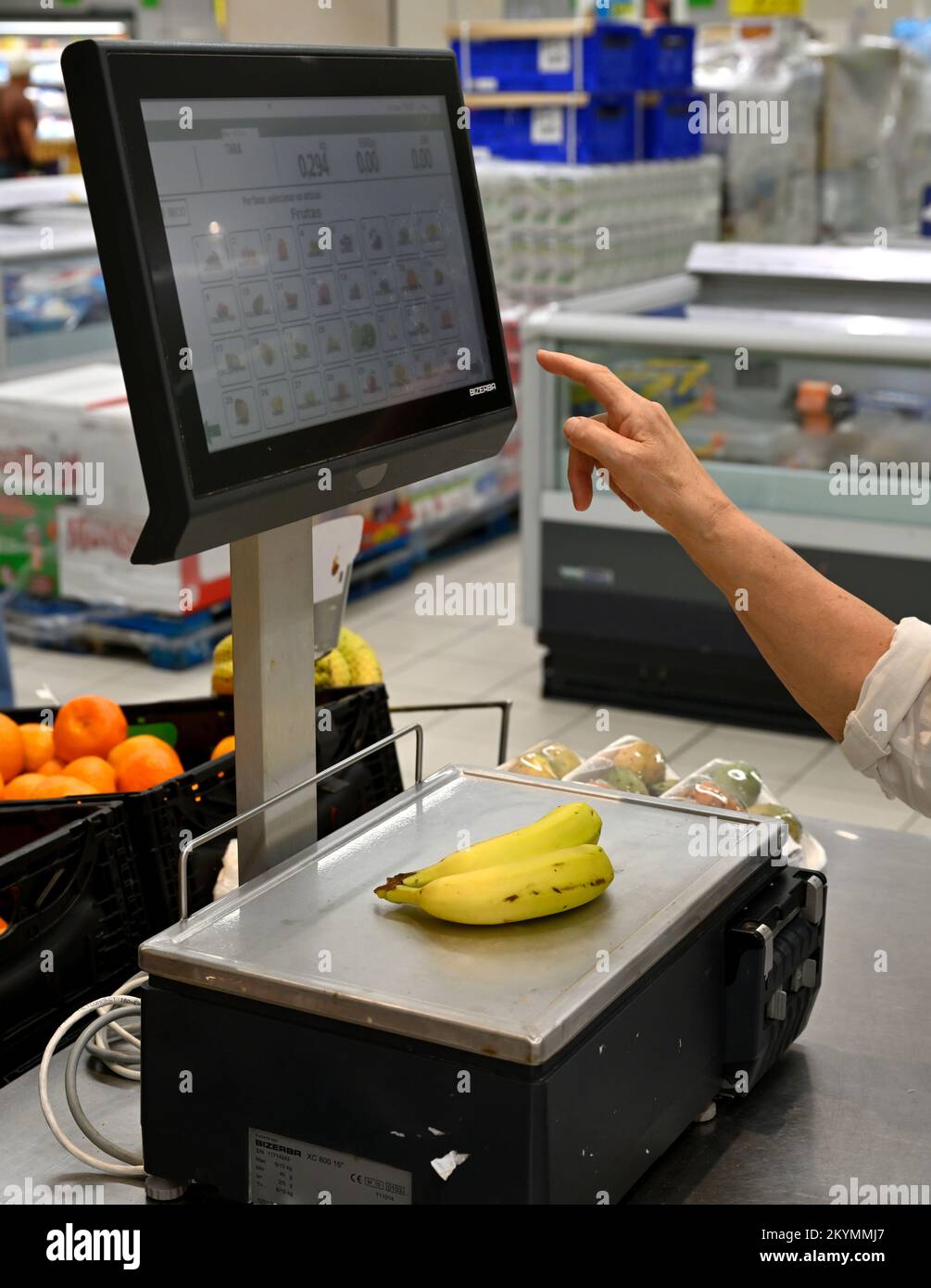 Customer using in-store electronic weighing scale with product display ...