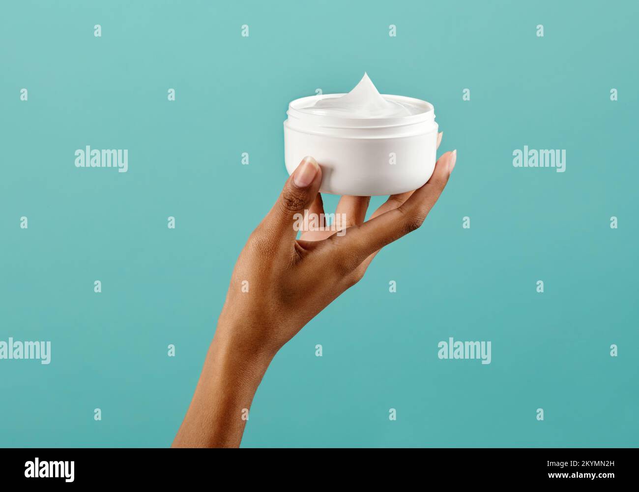 Crop hand of black female performing body lotion in blank white jar ...