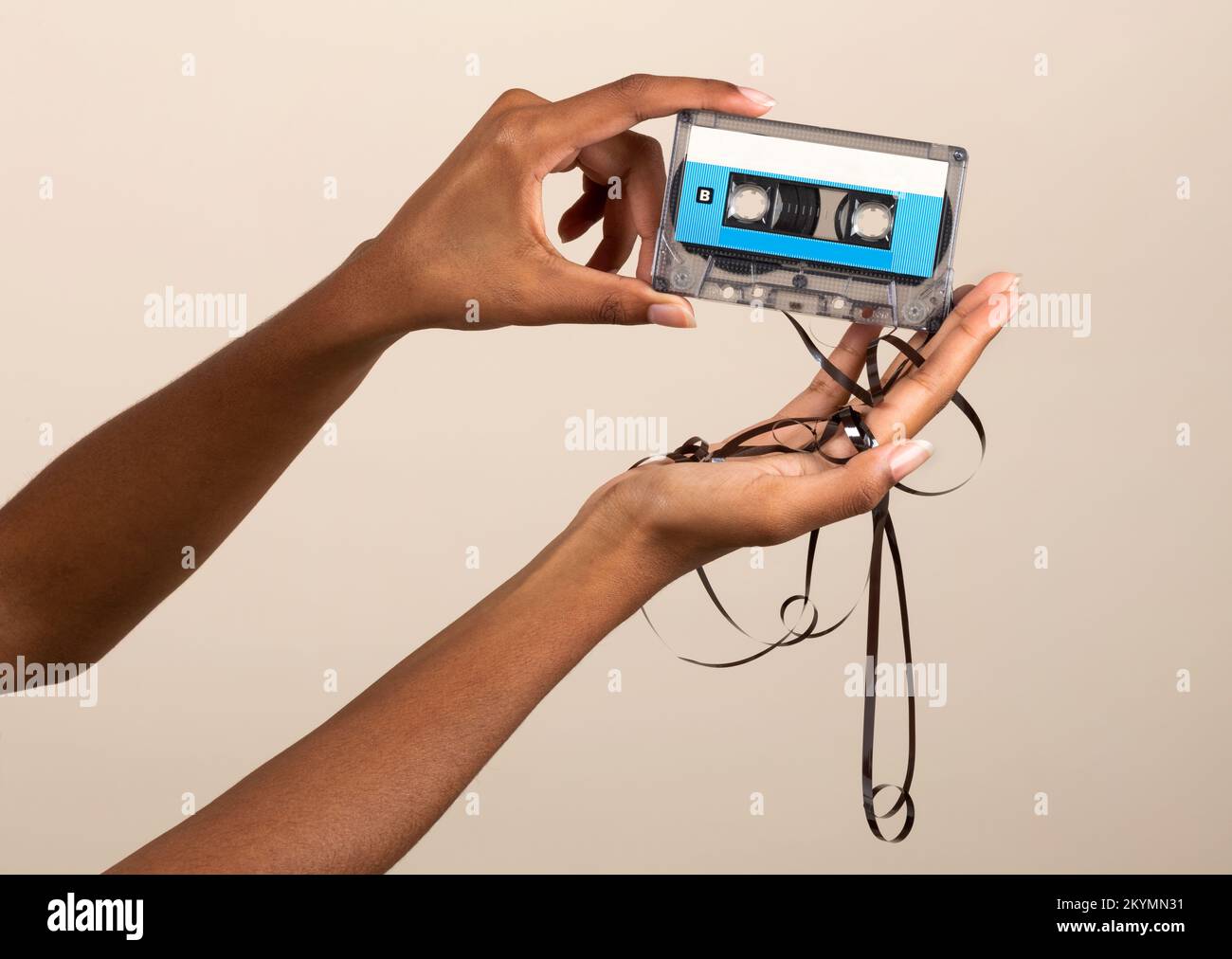 Crop hands of black woman demonstrating tape cassette with tape out ...