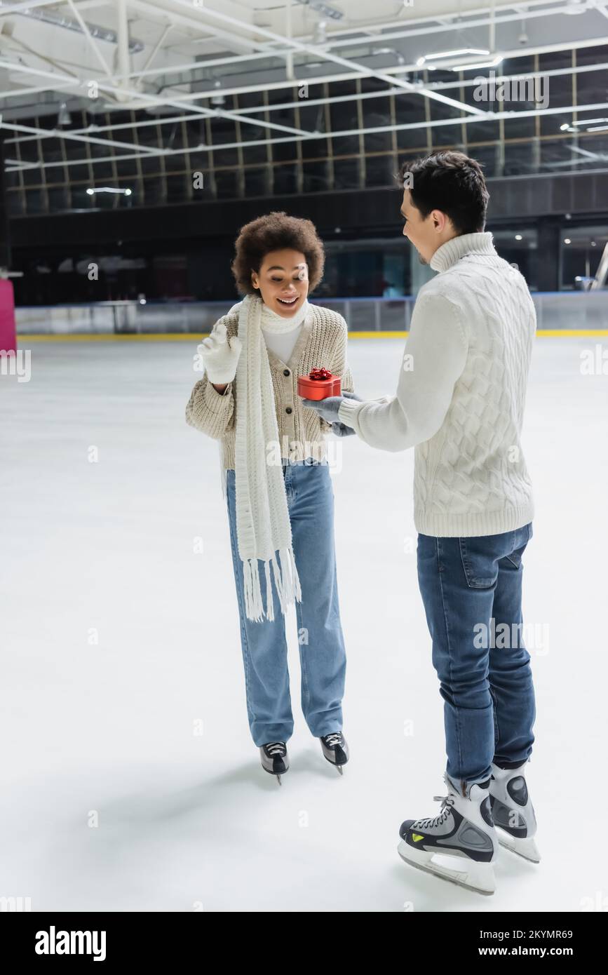 Smiling african american woman looking at heart shaped gift near ...
