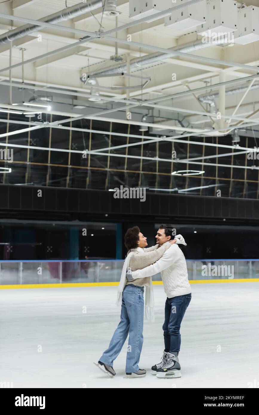 Side view of cheerful african american woman embracing boyfriend on ice ...