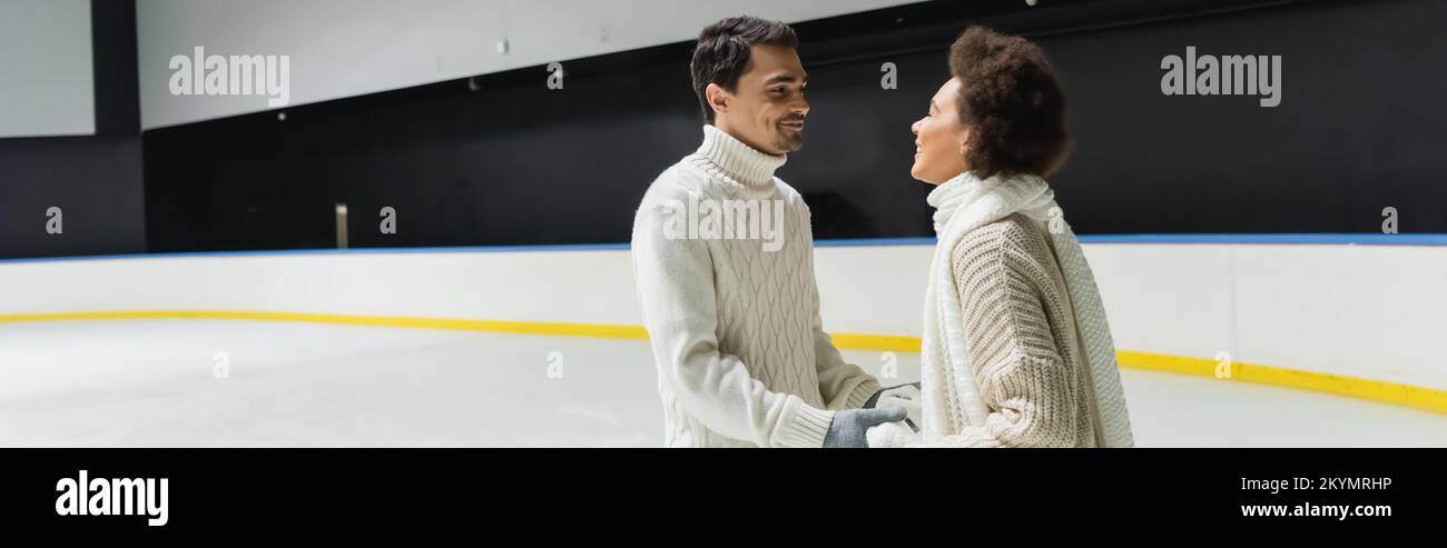 Cheerful interracial couple holding hands on ice rink, banner Stock ...