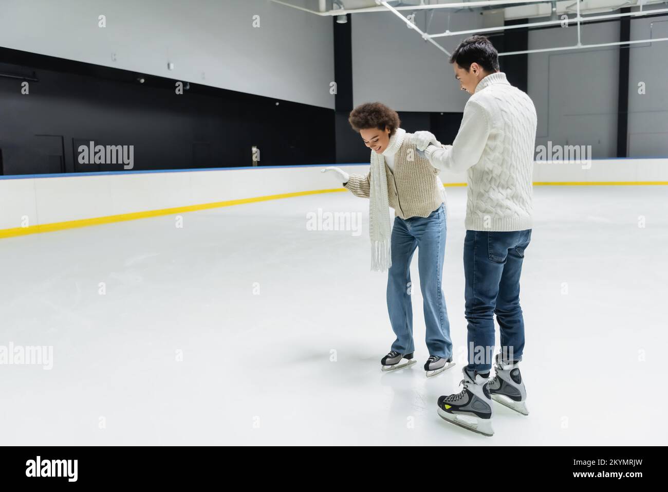 African american woman ice skating and holding hand of boyfriend on ice ...