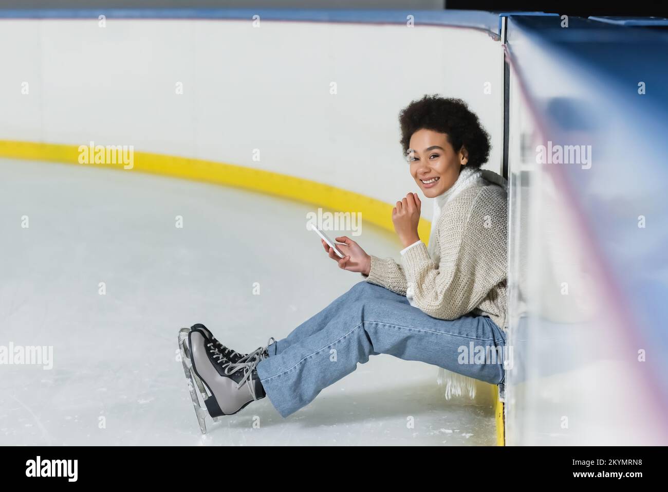 Positive african american woman holding smartphone and looking at ...