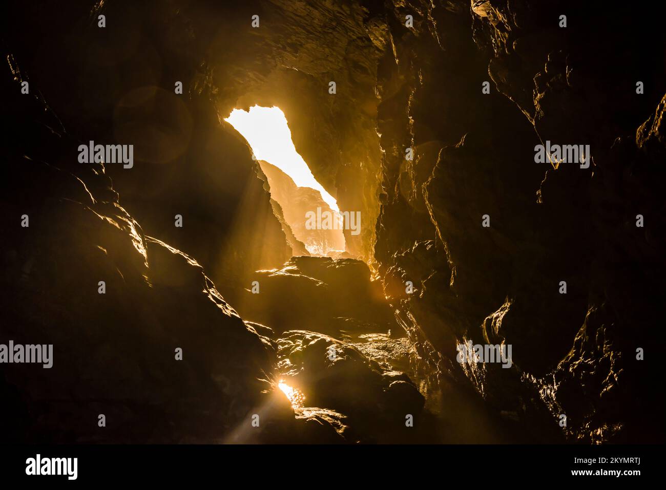 Setting sunlight shining through Merlin's Cave at Tintagel Haven ...