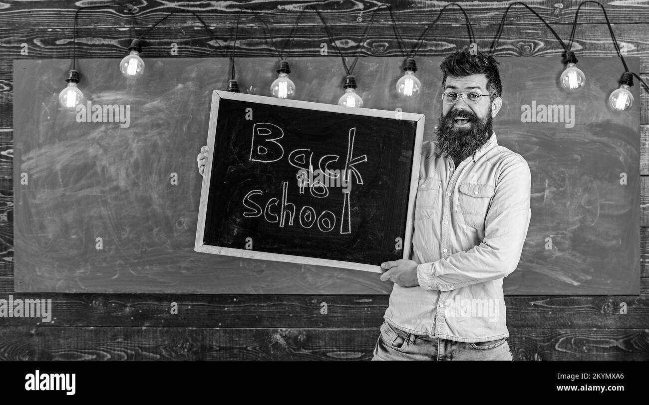 Teacher in eyeglasses holds blackboard with title back to school. Man ...