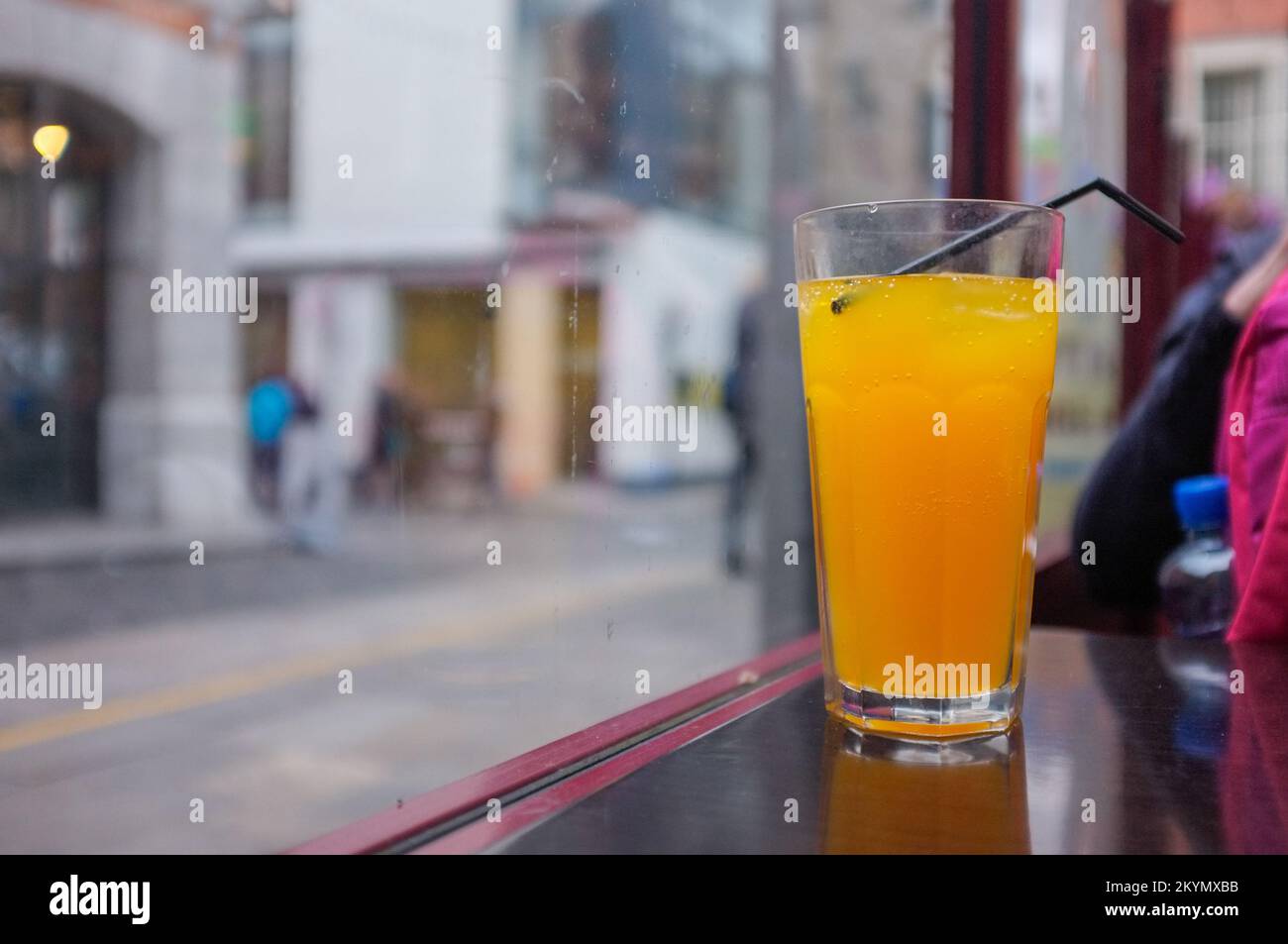 Glass of orange juice on a bar at a window with a view of the street ...