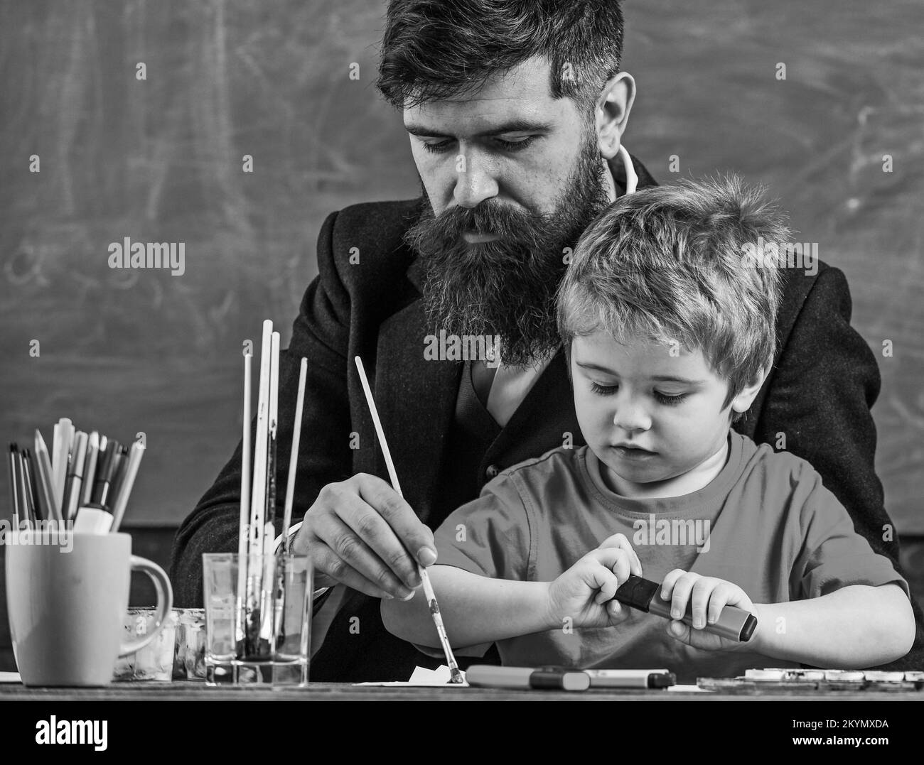 Teacher with beard, father and little son in classroom while drawing ...