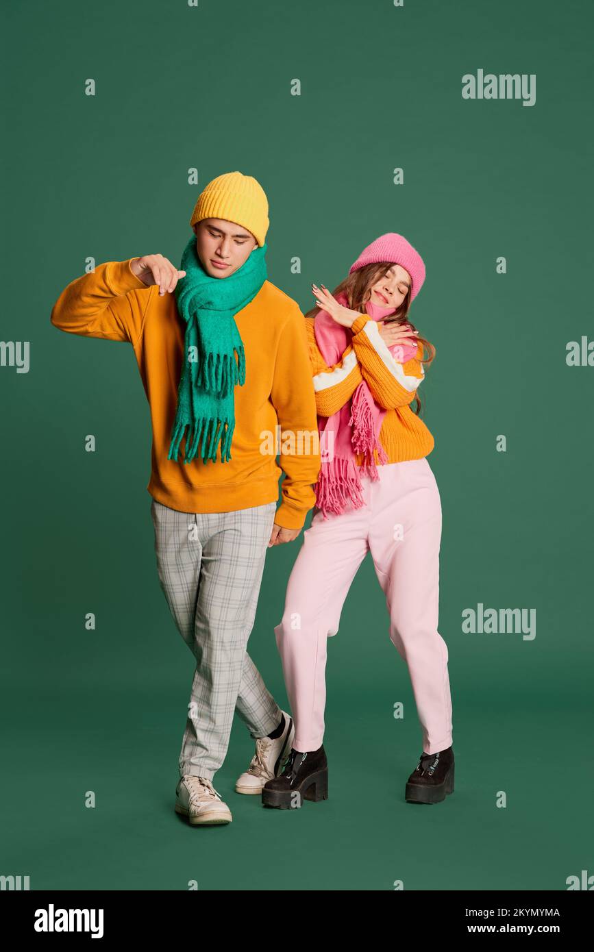 Portrait of young man and woman in bright knitted hat and scarf posing ...