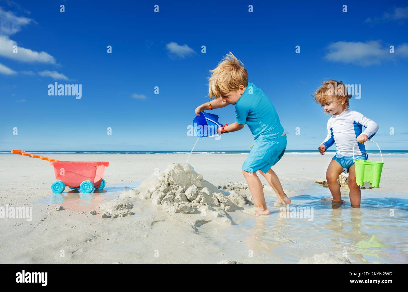 Cute little blond boy play with sand pouring water from bucket Stock ...