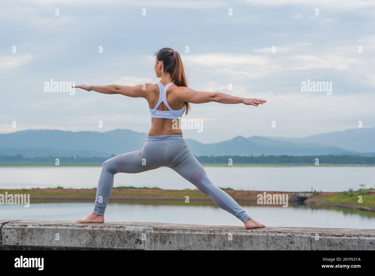 Young Asian woman doing Yoga exercise in beautiful lake with mountain ...