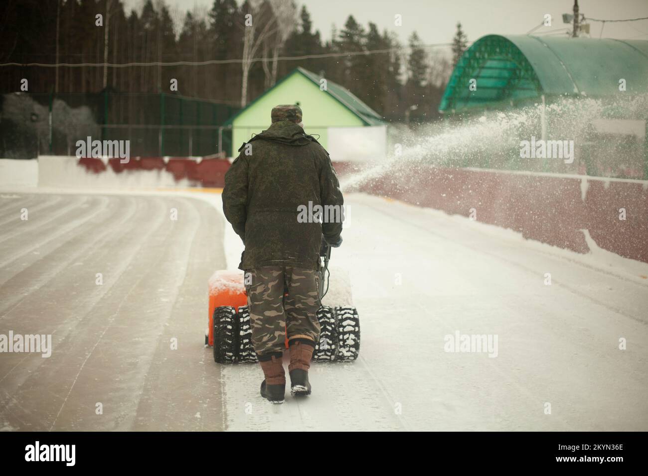 Snow removal at ice rink. Removal of layer of snow from ice. Worker ...