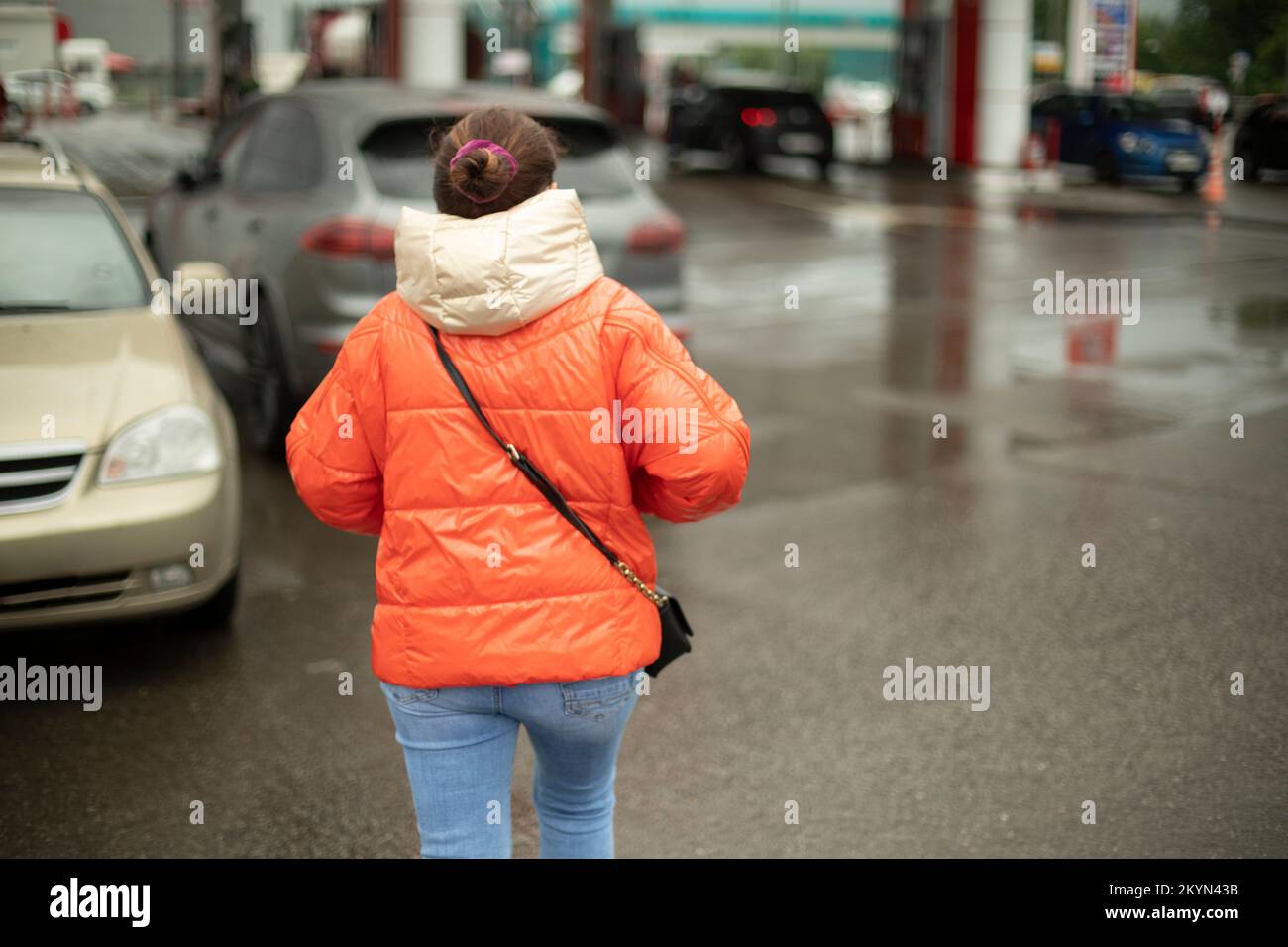 Girl goes to gas station with gasoline. Woman in parking lot. Man on ...