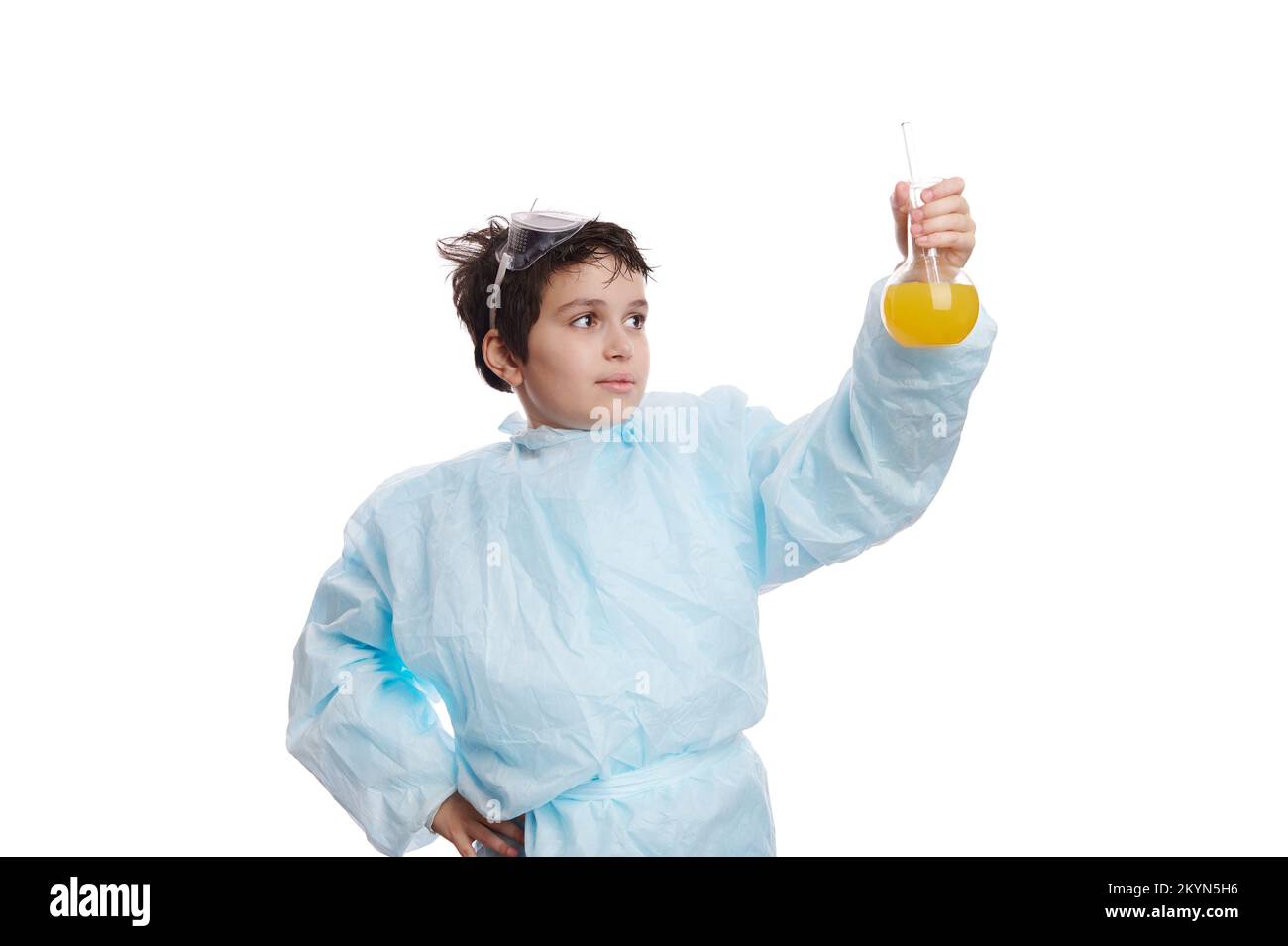 Smart teenage boy, young chemist observing chemical reaction going on ...