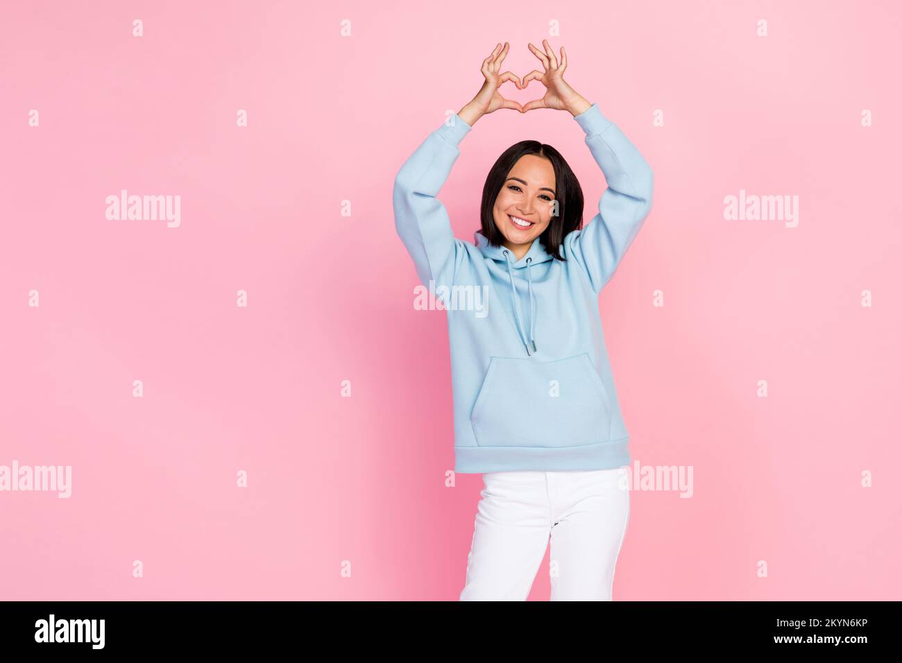 Photo of sweet cute lady wear blue hoodie rising arms showing heart ...