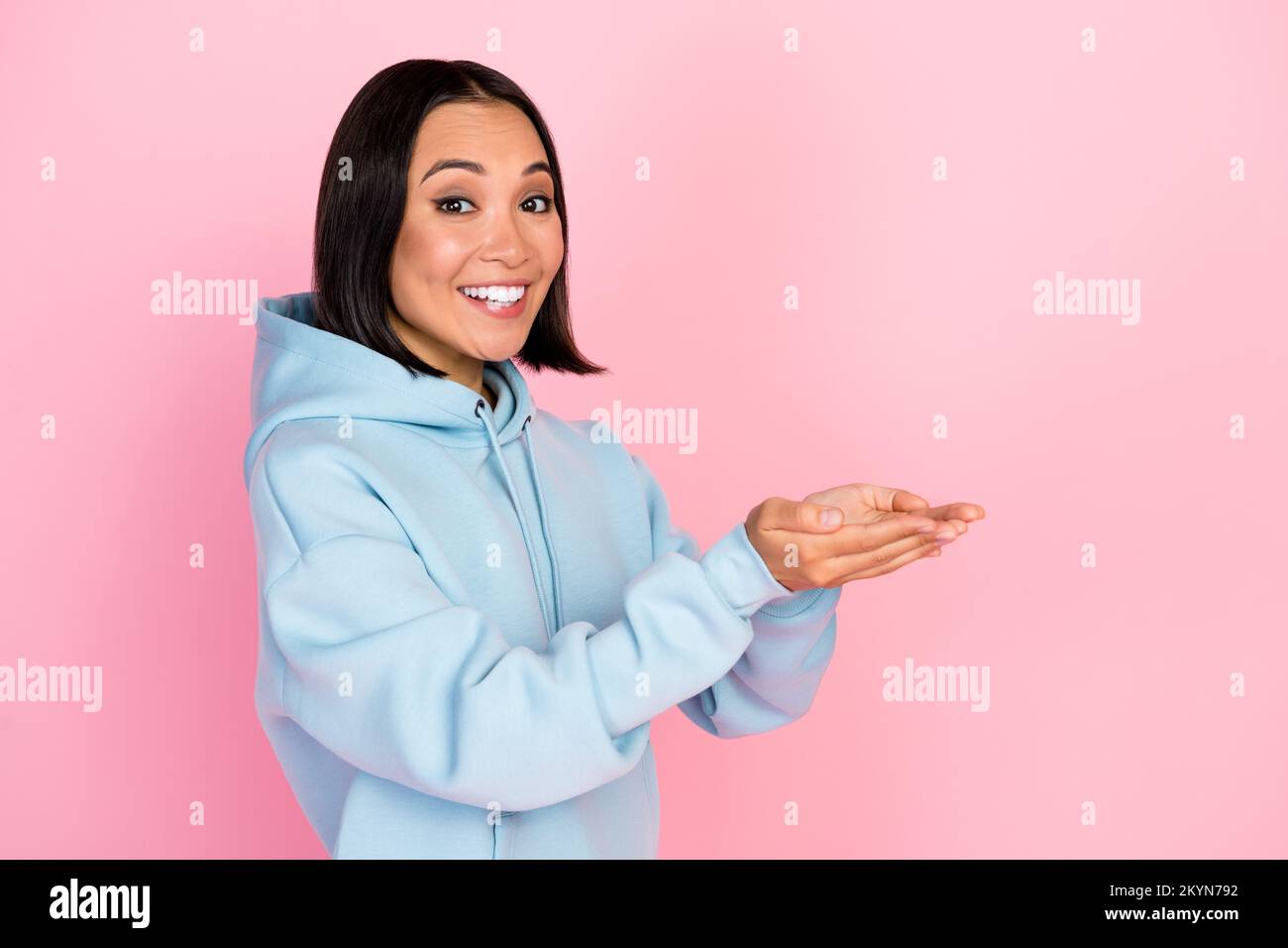 Photo of sweet excited lady wear blue hoodie holding arms empty space ...