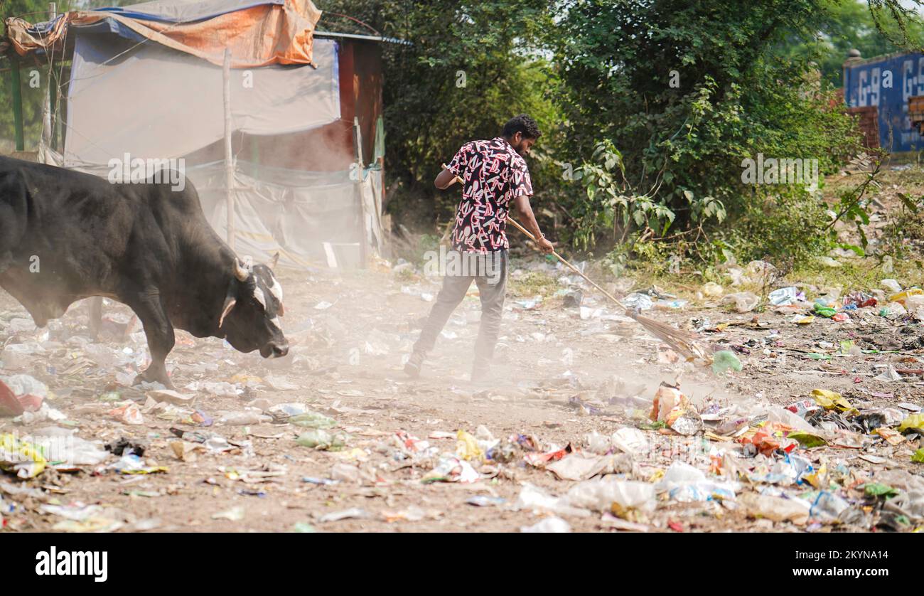 Man sweeping the trash with broom and polyhthene big garbage area, Man ...