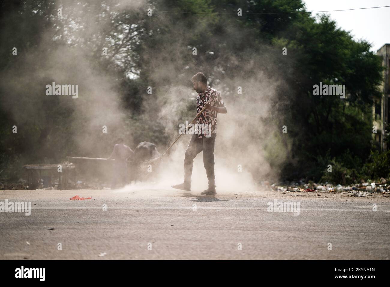 Man sweeping the trash with broom and polyhthene street or road side ...