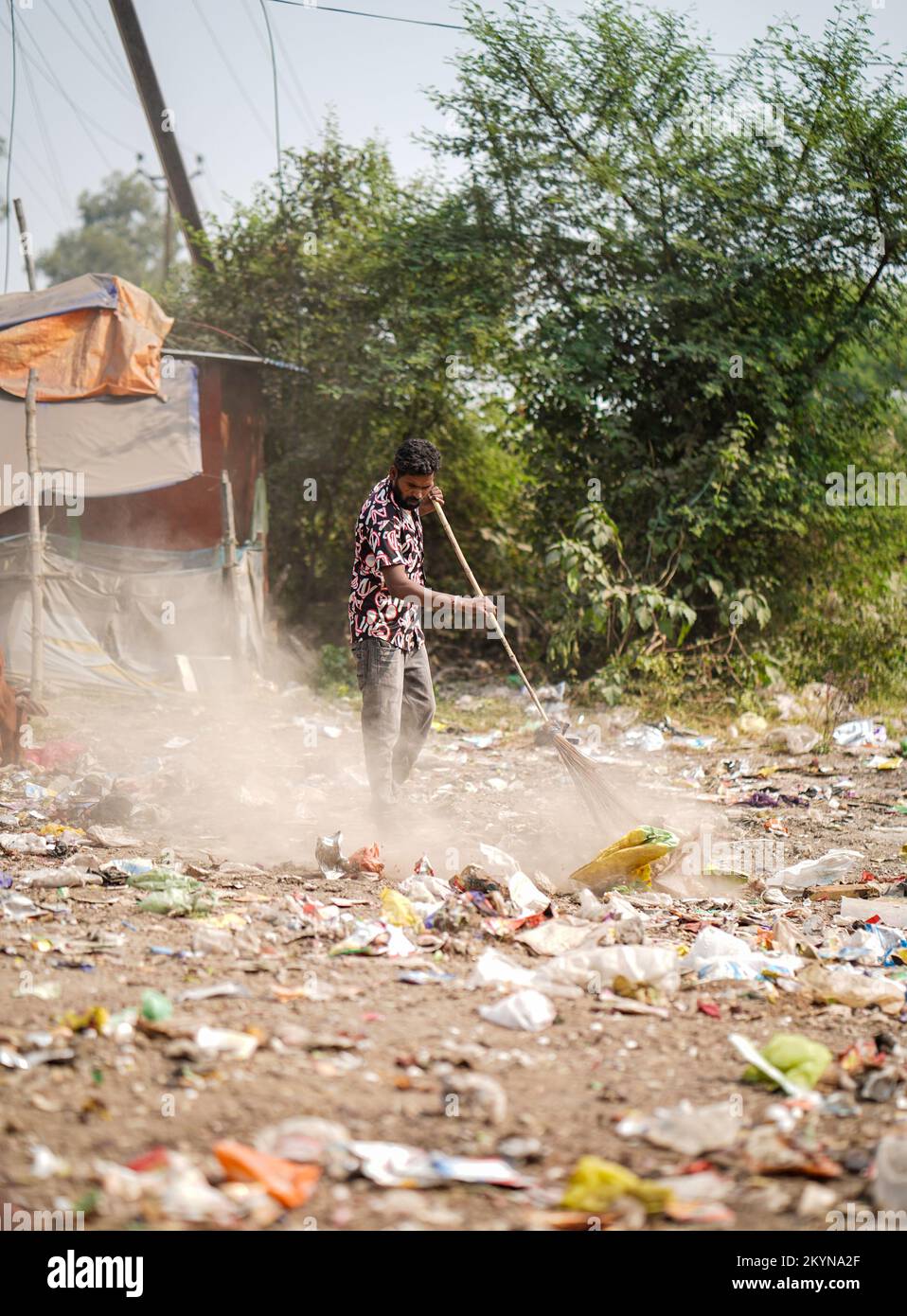 Man sweeping the trash with broom and polyhthene big garbage area, Man ...