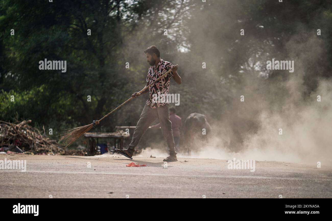 Man sweeping the trash with broom and polyhthene big garbage area, Man ...