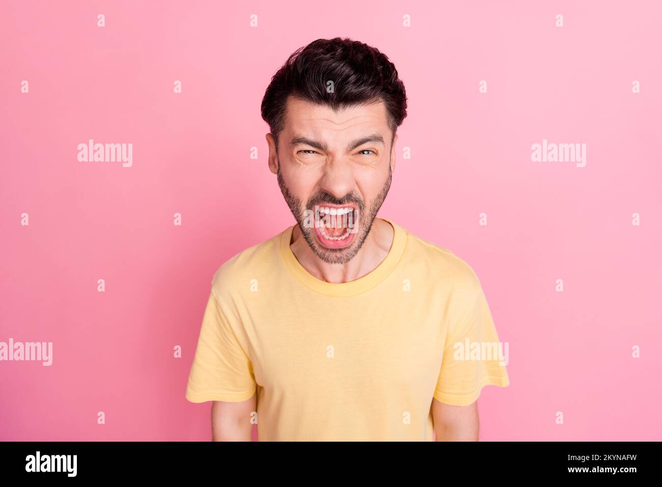 Portrait of angry screaming mad man with stylish haircut wear yellow t ...