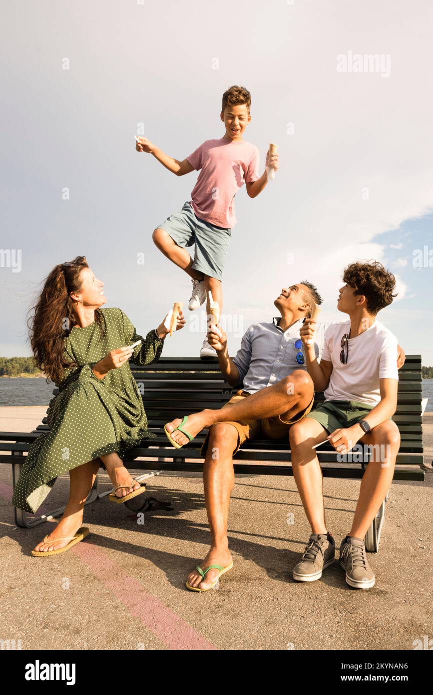 Family looking at boy balancing on bench during vacation Stock Photo ...