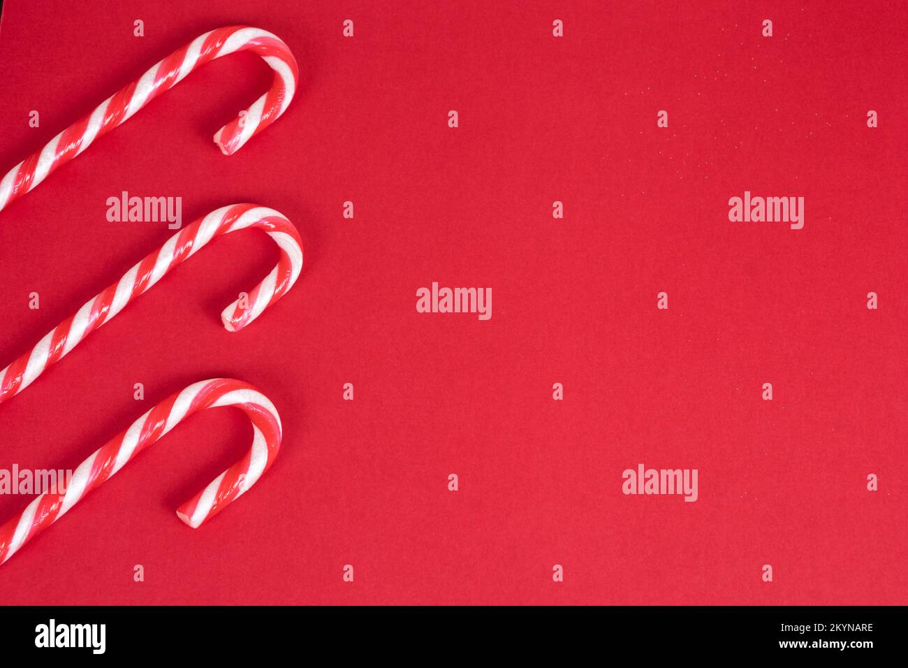 Three red and white candy canes on red christmas background, top view ...