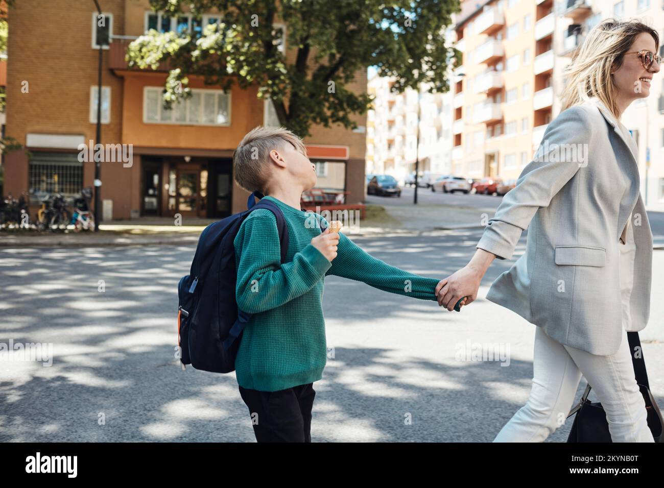 Side view of woman taking stubborn son to school while walking on ...