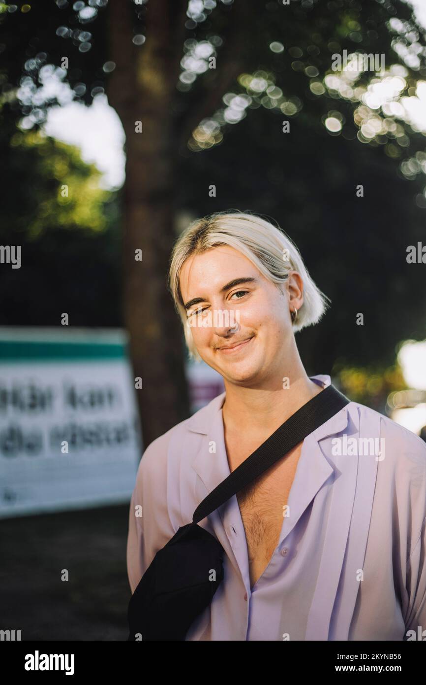 Portrait of smiling non-binary person with medium-length hair winking ...