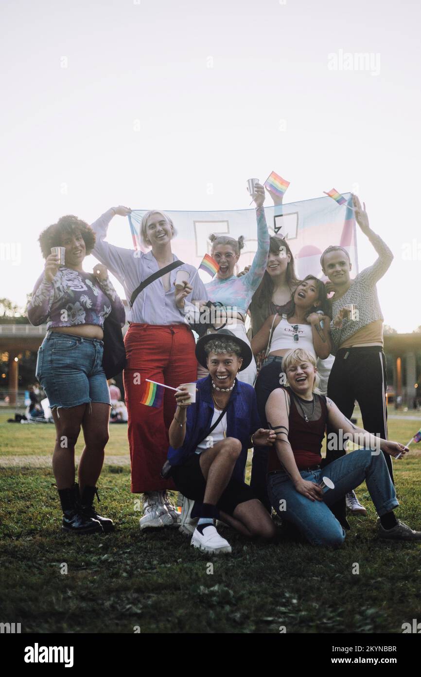 Portrait of cheerful friends enjoying gay pride parade at park during ...