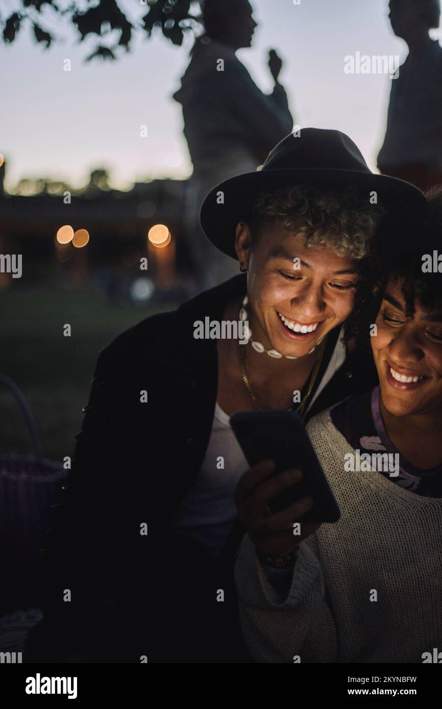 Happy transgender woman sharing mobile phone with male friend during ...