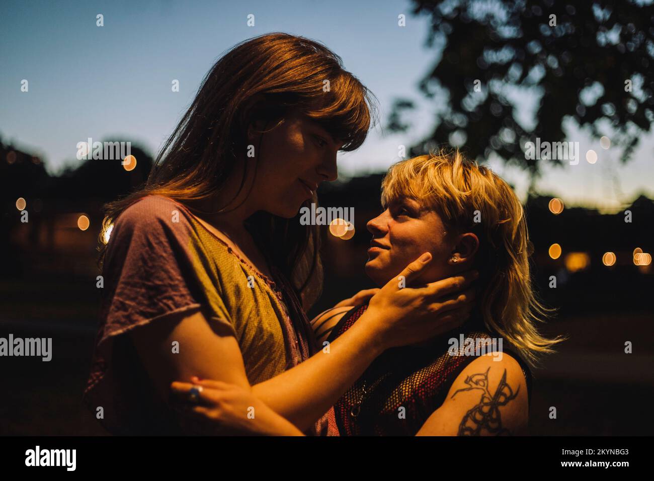 Young transgender woman looking at non-binary person at night Stock ...