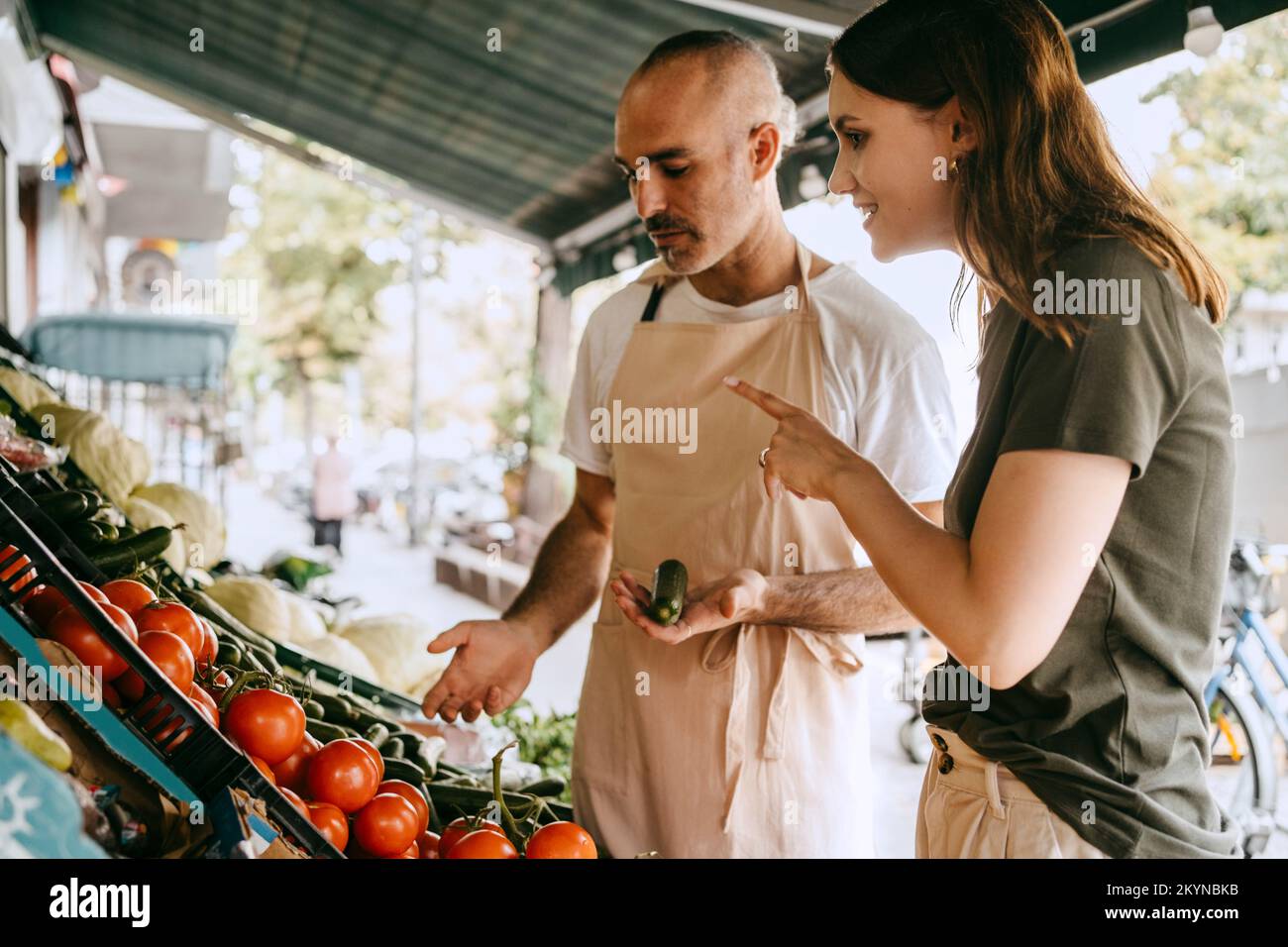 Side view of female customer gesturing while talking to male vendor ...