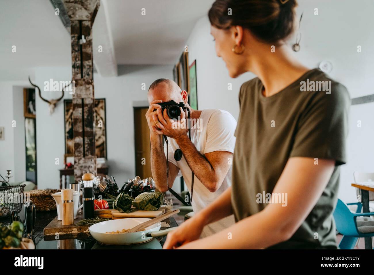 Male photographer taking picture of female chef cooking food in studio ...