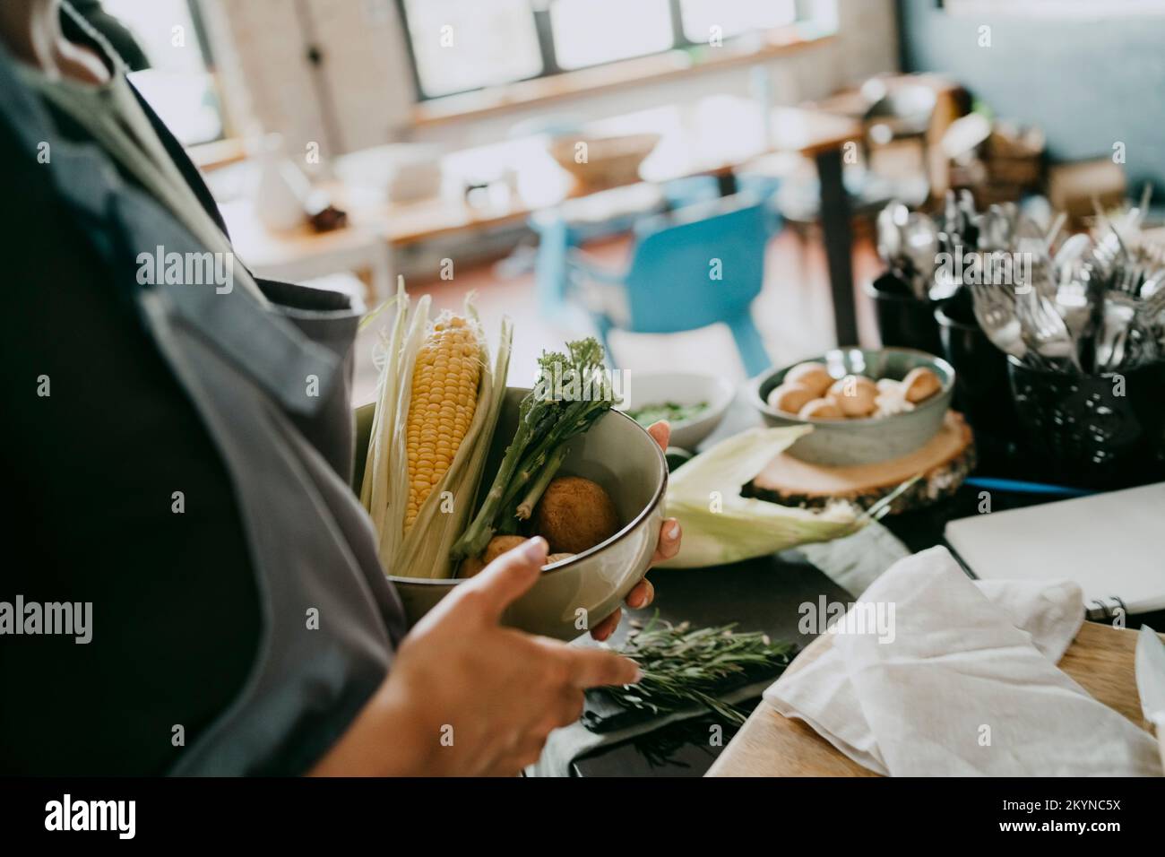 Midsection of female chef holding bowl of vegetables in studio kitchen ...