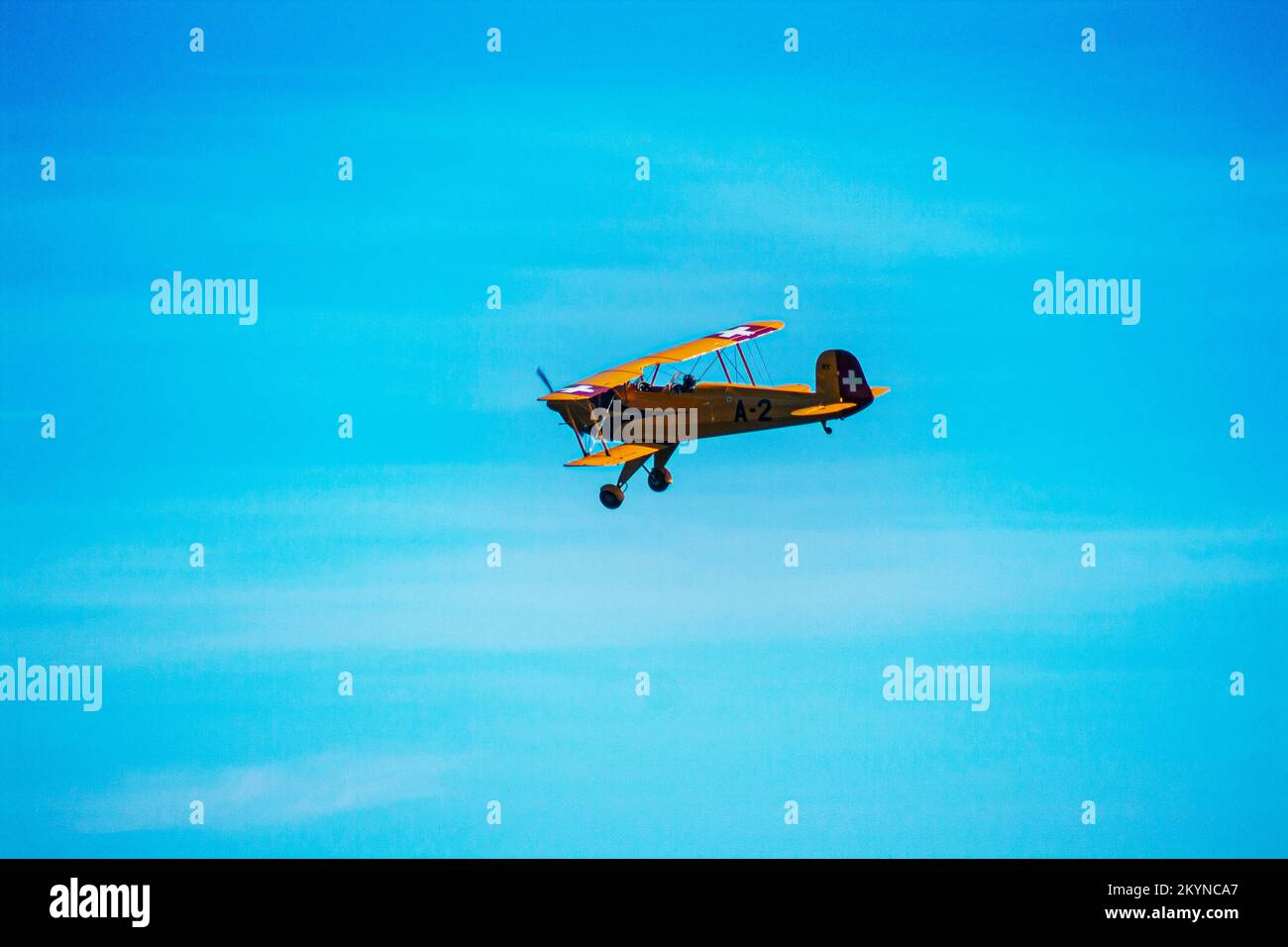 A small yellow airplane flying against a blue sky Stock Photo - Alamy