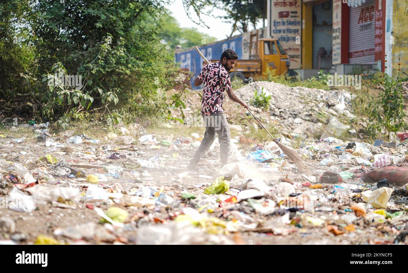 Man sweeping the trash with broom and polyhthene big garbage area, Man ...