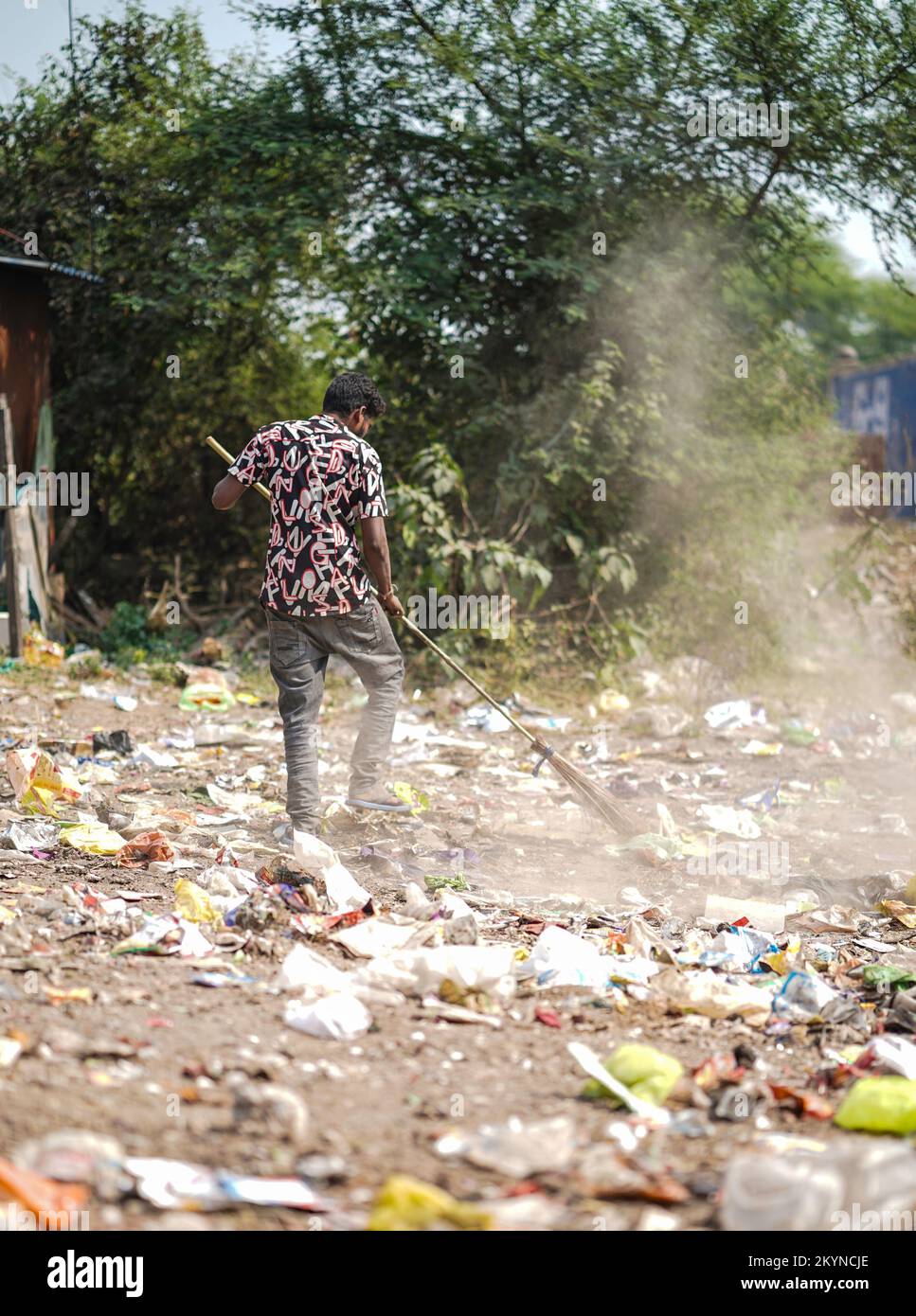 Man sweeping the trash with broom and polyhthene big garbage area, Man ...