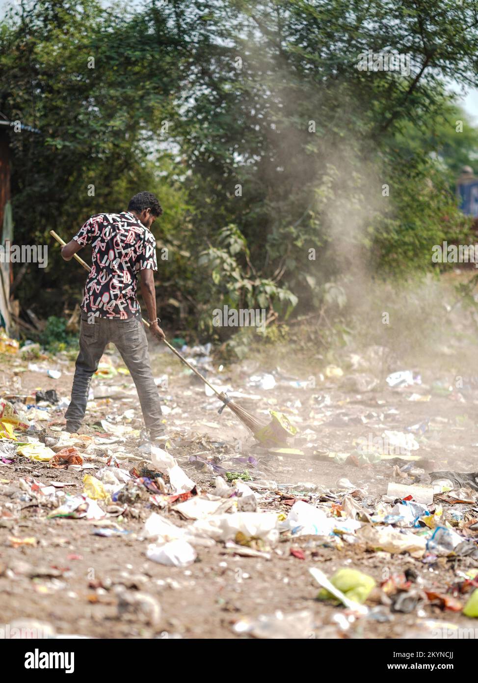 Man sweeping the trash with broom and polyhthene big garbage area, Man ...