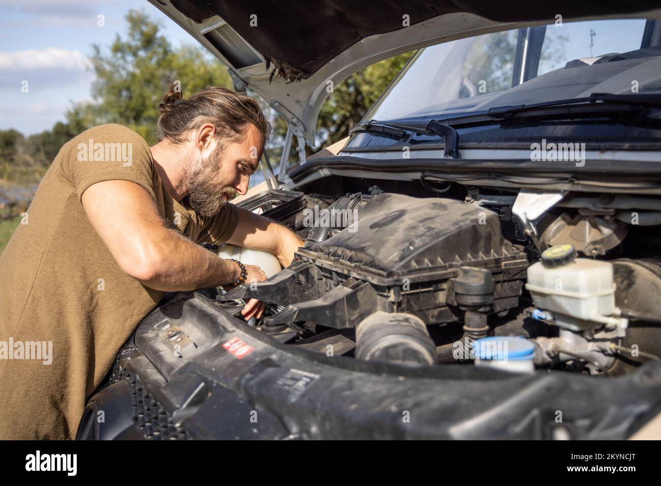 Man working in the engine compartment of a van outdoors Stock Photo - Alamy